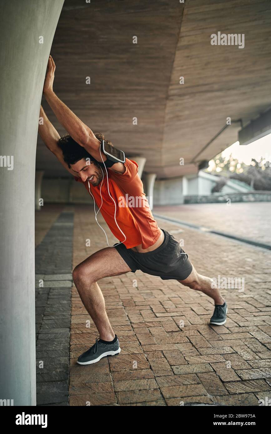 Side view of a cheerful fitness young male runner with electronic ...