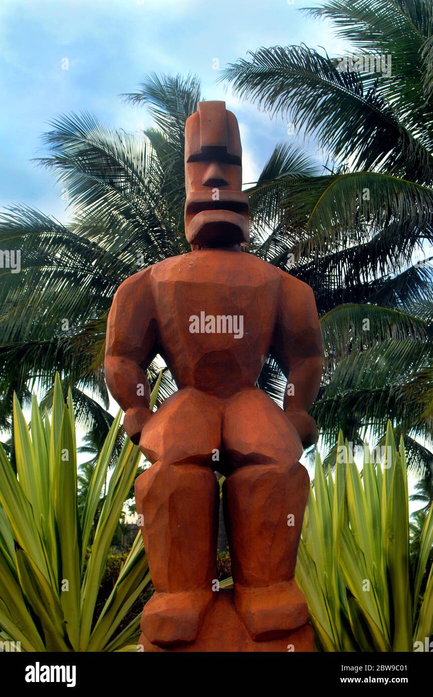Large wooden tiki stands guard in garden setting. Features are fierce ...