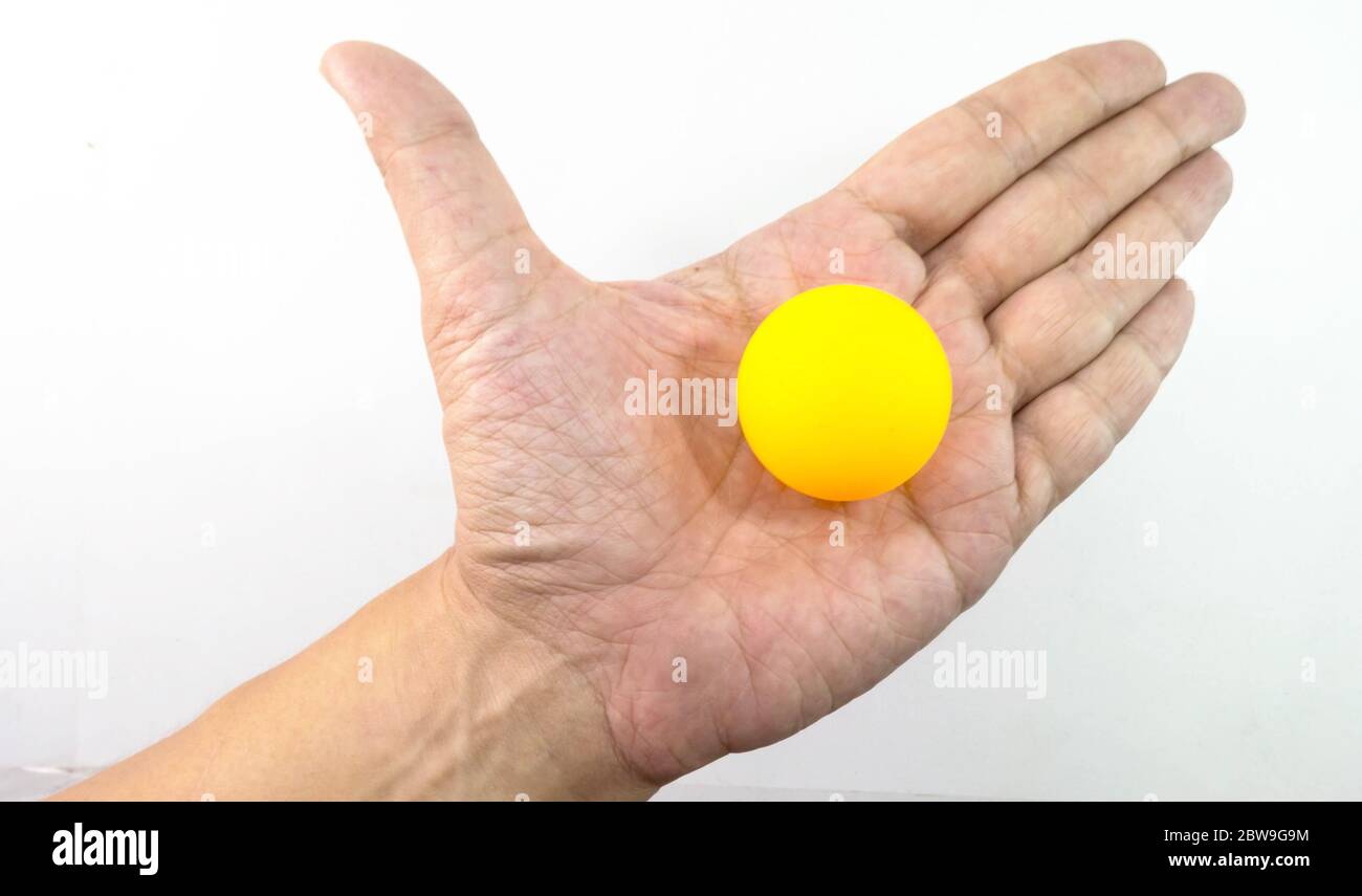 Man hand in hand with orange ping pong ball Stock Photo - Alamy