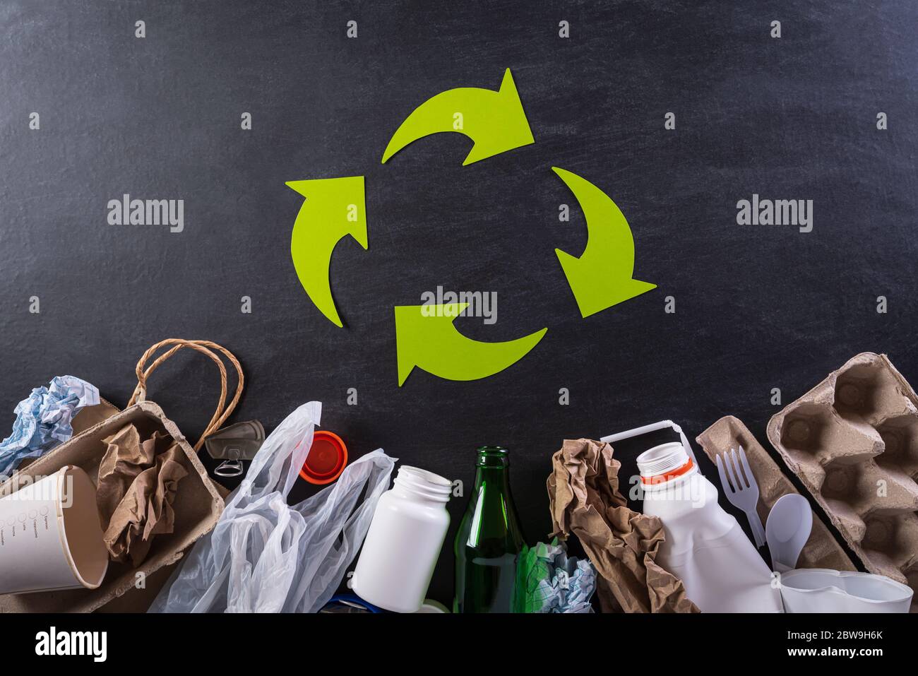Top view of Different garbage materials with recycling symbol on black ...