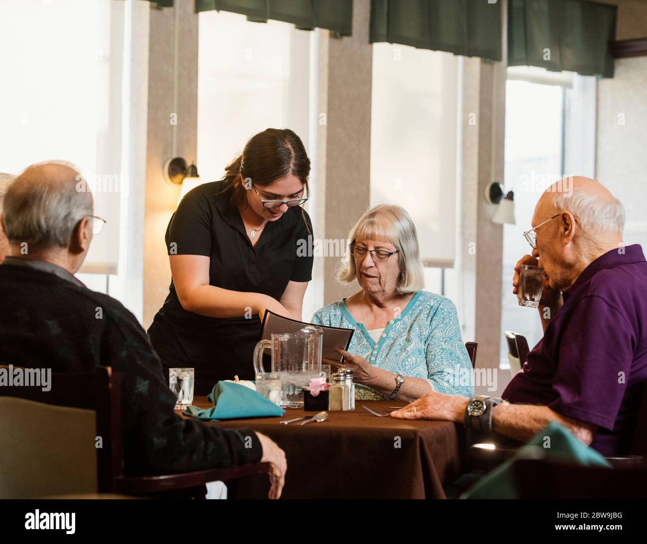 Waitress explaining menu to senior woman at table Stock Photo - Alamy