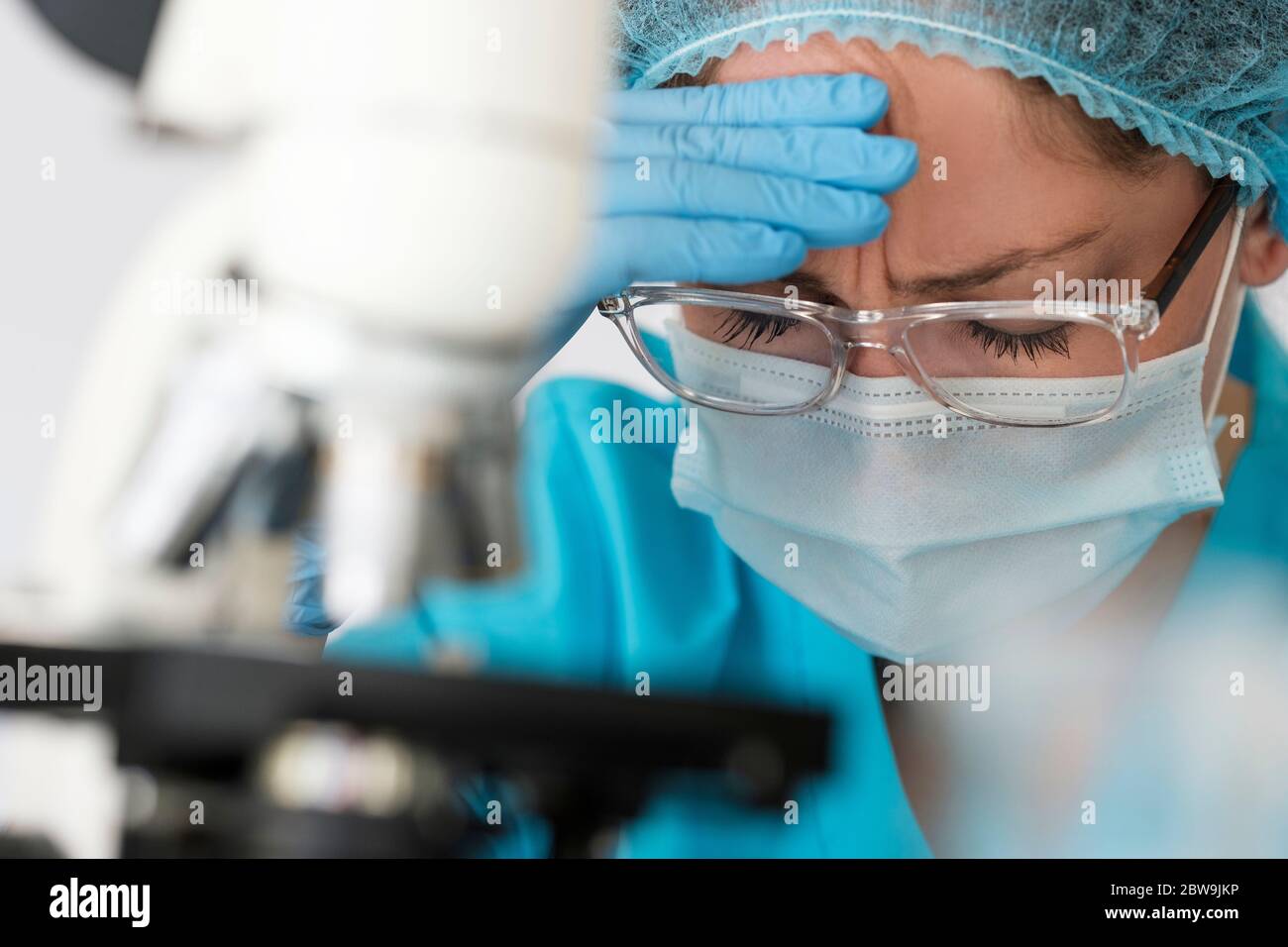 Healthcare professional with face mask using microscope Stock Photo - Alamy