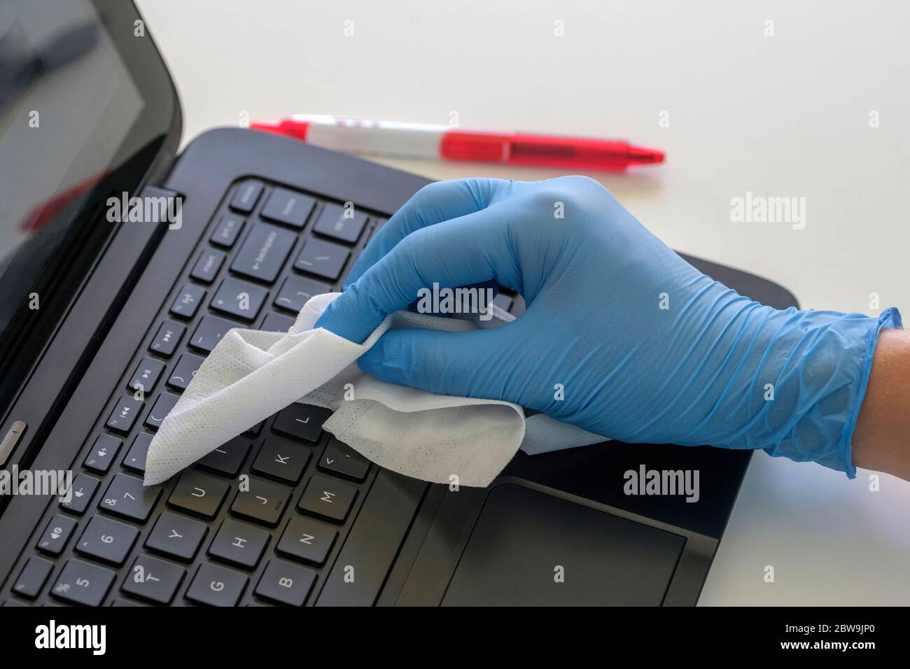 Person wearing blue surgical glove cleaning keyboard of laptop Stock ...