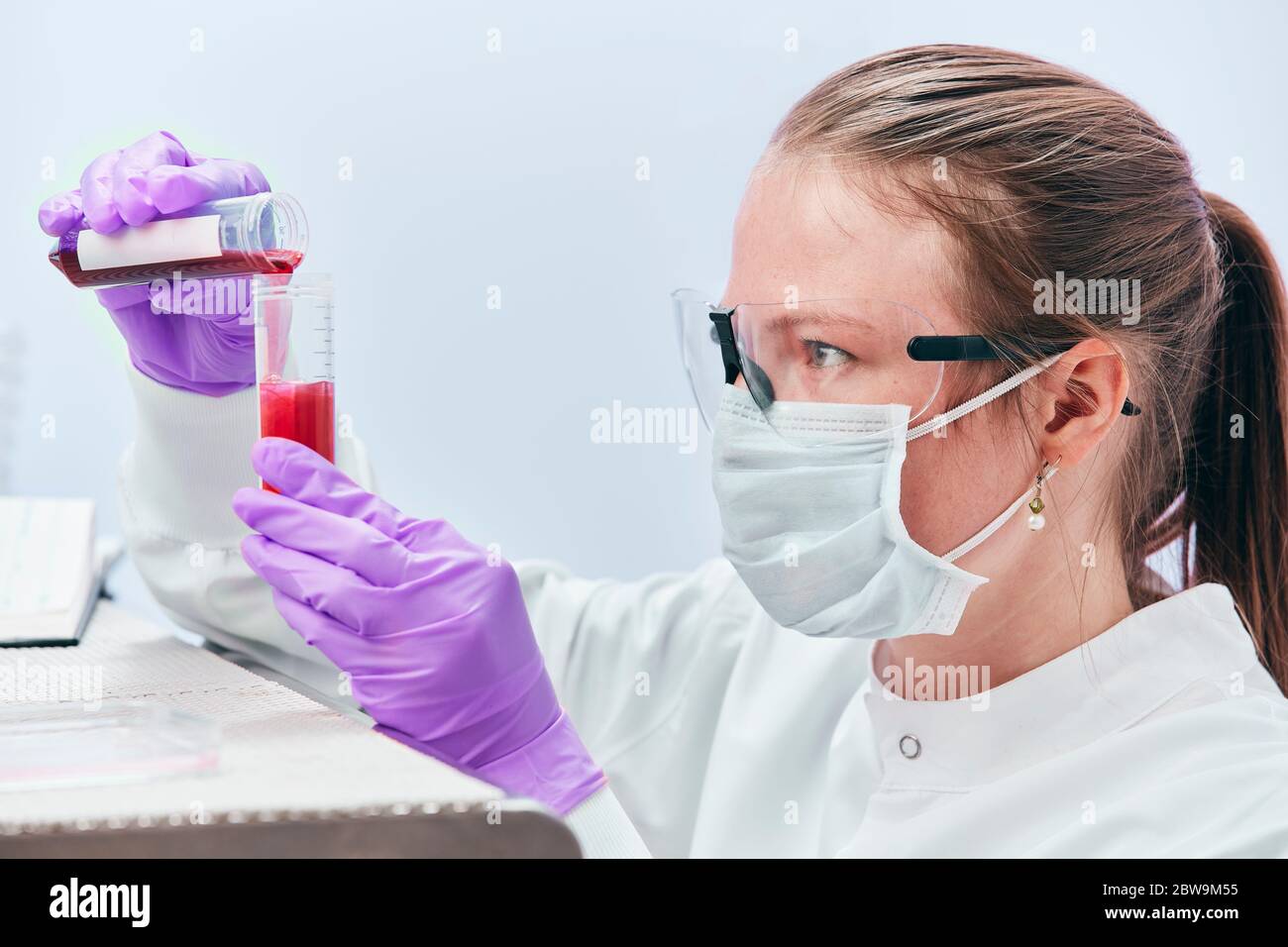 Female technician pouring liquid into vial Stock Photo - Alamy