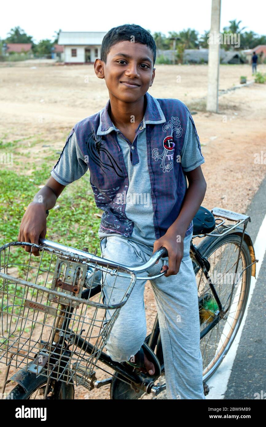 A Muslim boy riding a bicycle stops on the road side in the late ...