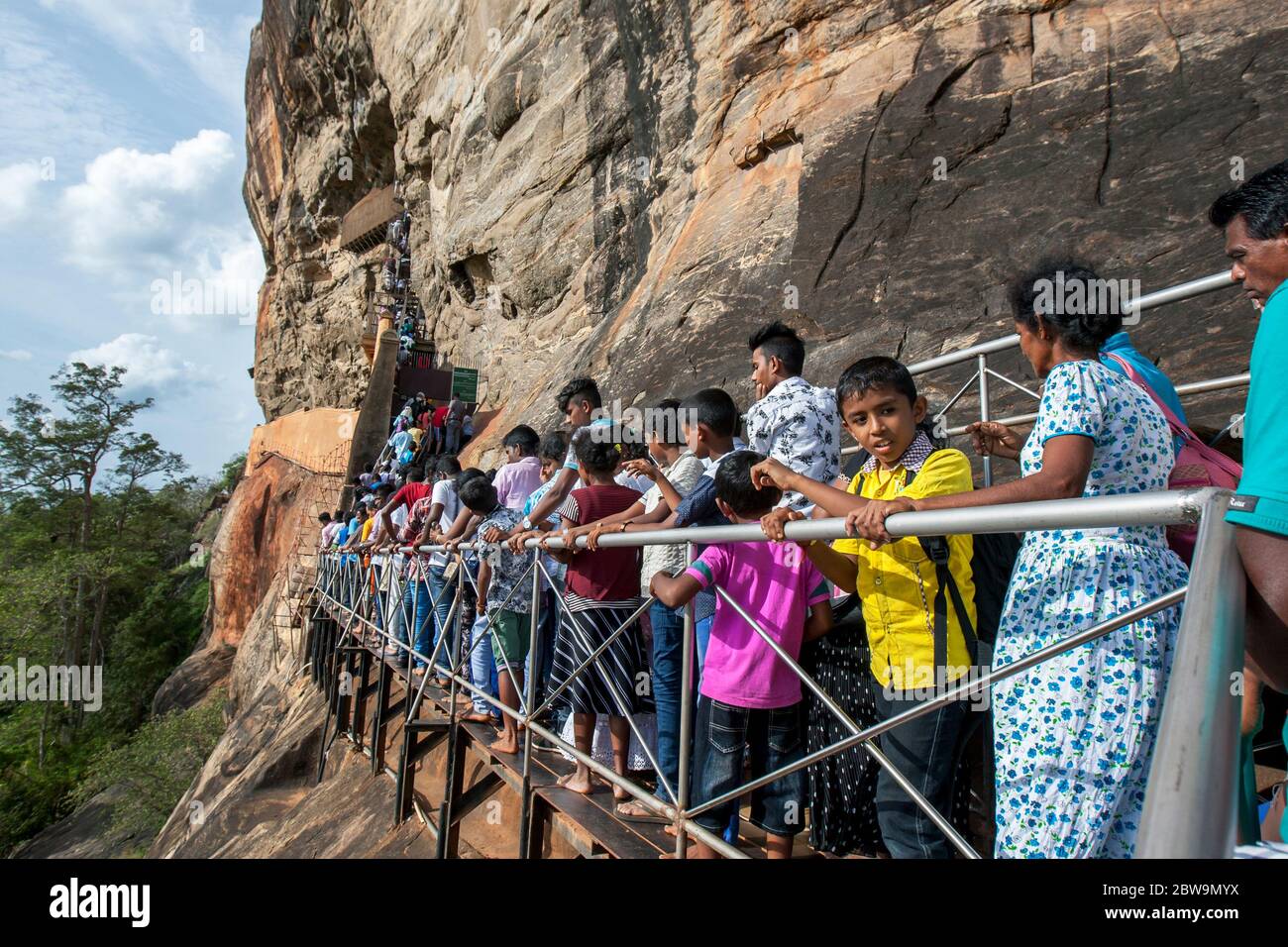 A crowd of people moving along a walkway on Sigiriya Rock Fortress in ...
