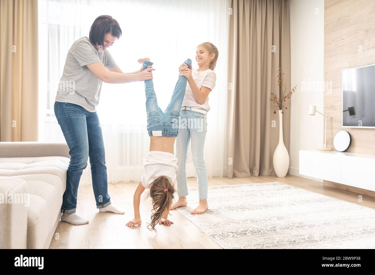 Happy mother and two daughters having fun in living room. mom holding ...