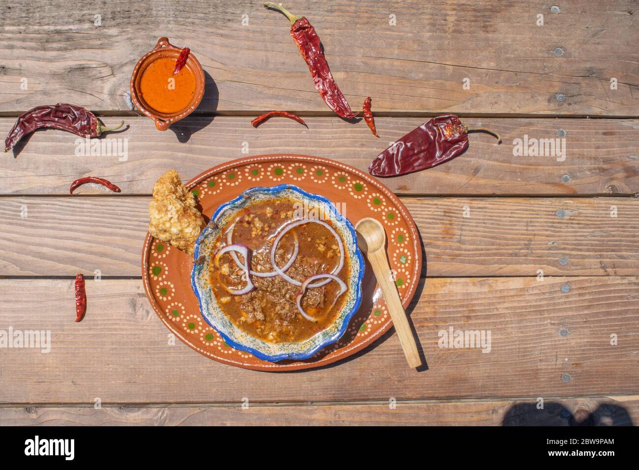 Mexican food, plate of birria with sauce and Mexican chili peppers ...
