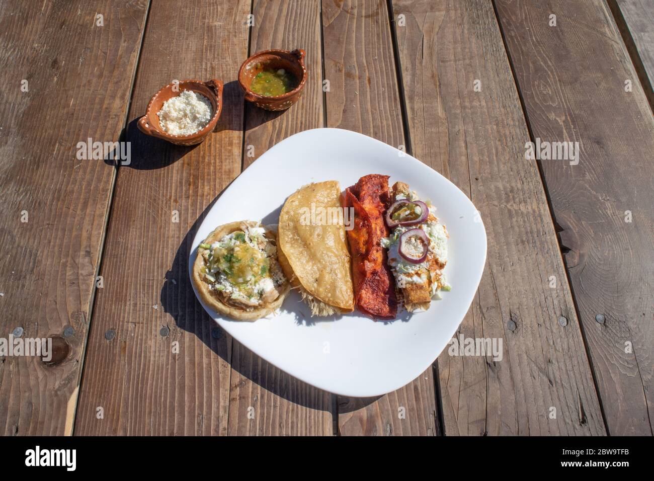 plate with variety of mexican food like sope, tacos and enchilada With ...