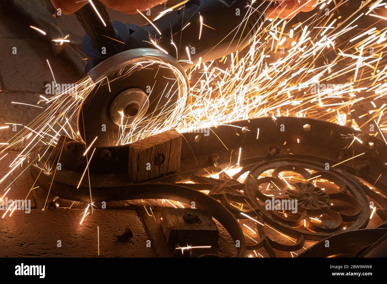 Side view of a man's hands working on a metal part of a garden bench ...