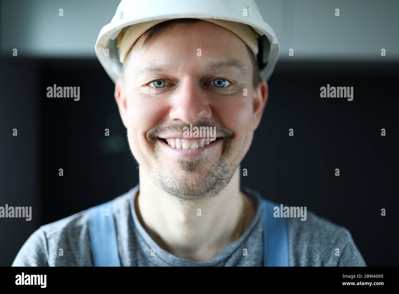 Happy builder man in helmet stands in apartment Stock Photo - Alamy