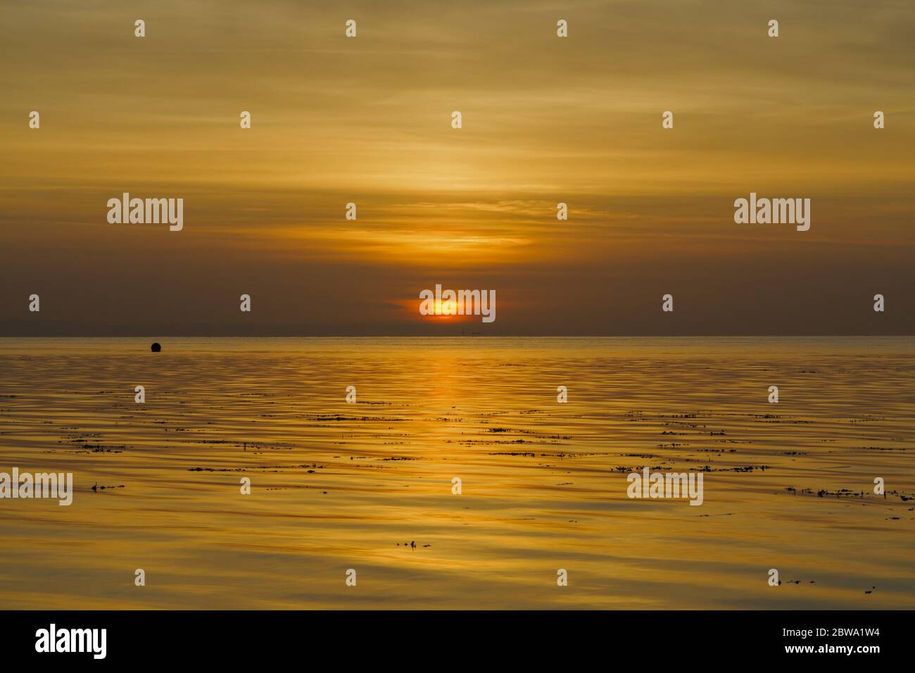 The sun setting over the horizon Stock Photo - Alamy