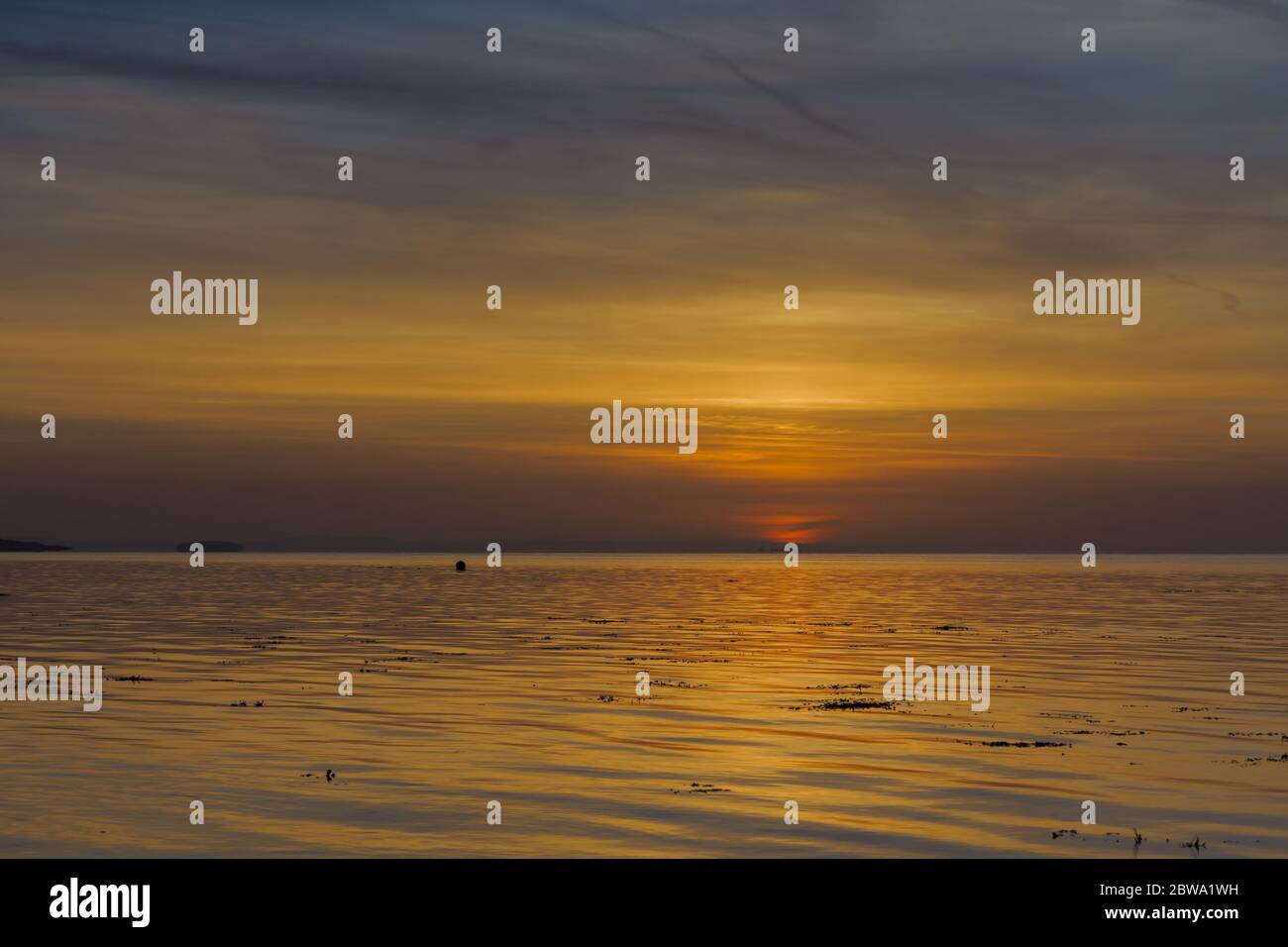 The sun setting over the horizon Stock Photo - Alamy