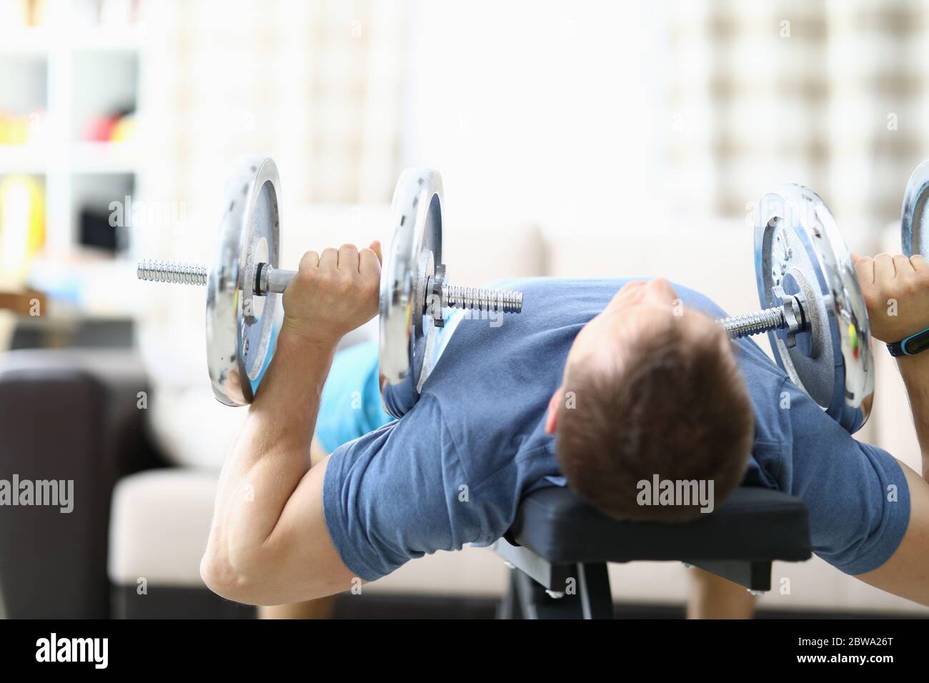 Man doing strength exercises with dumbbells home Stock Photo - Alamy