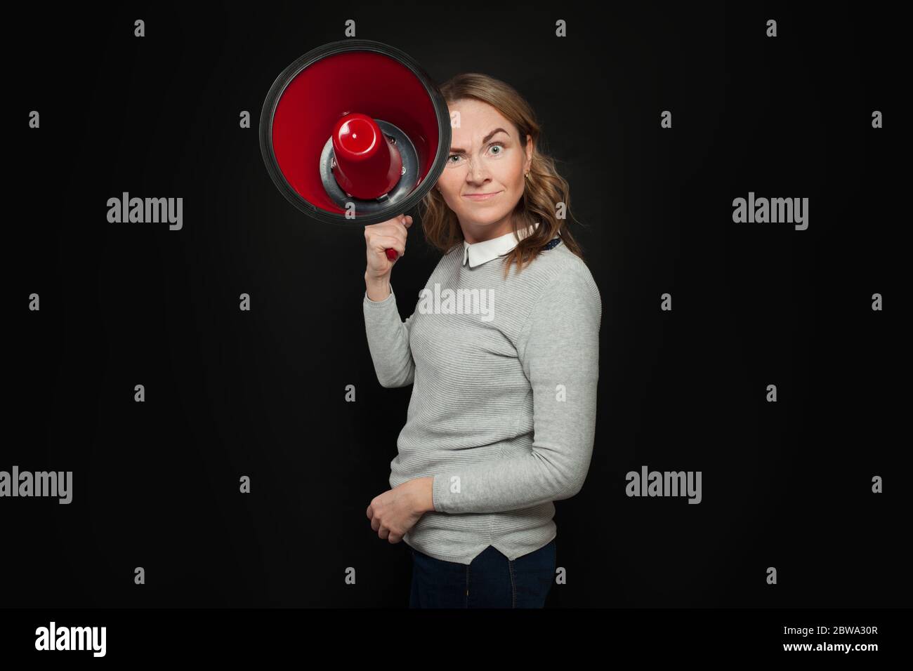 Girl holding big red bullhorn on black background. Woman with ...