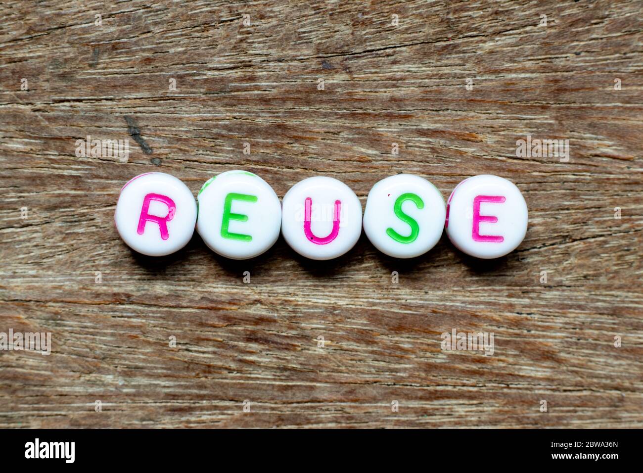 White bead with color letter in word reuse on wood background Stock ...