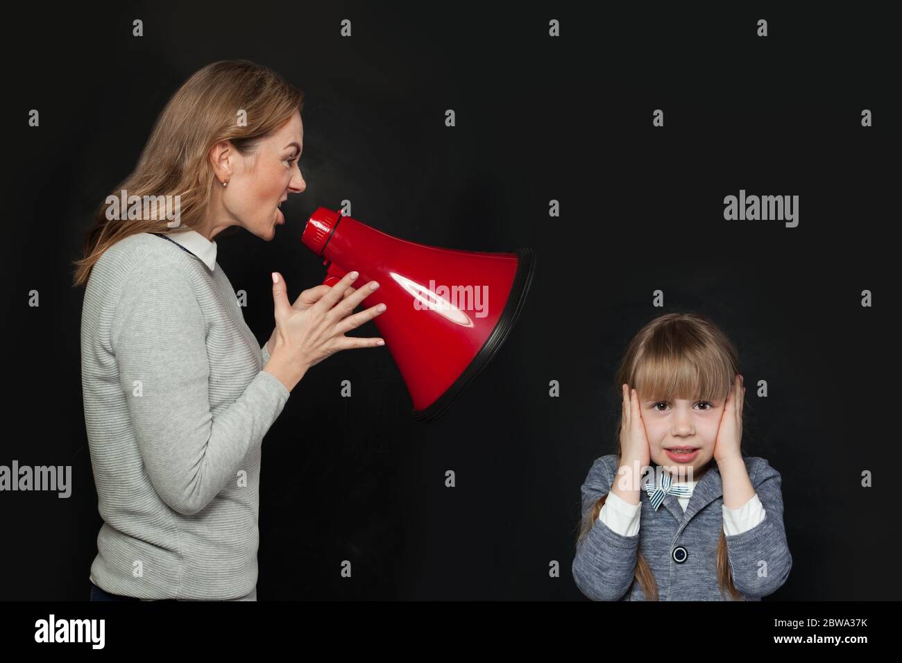 Mother shouting in loudspeaker to unhappy daughter. Sad child girl ...