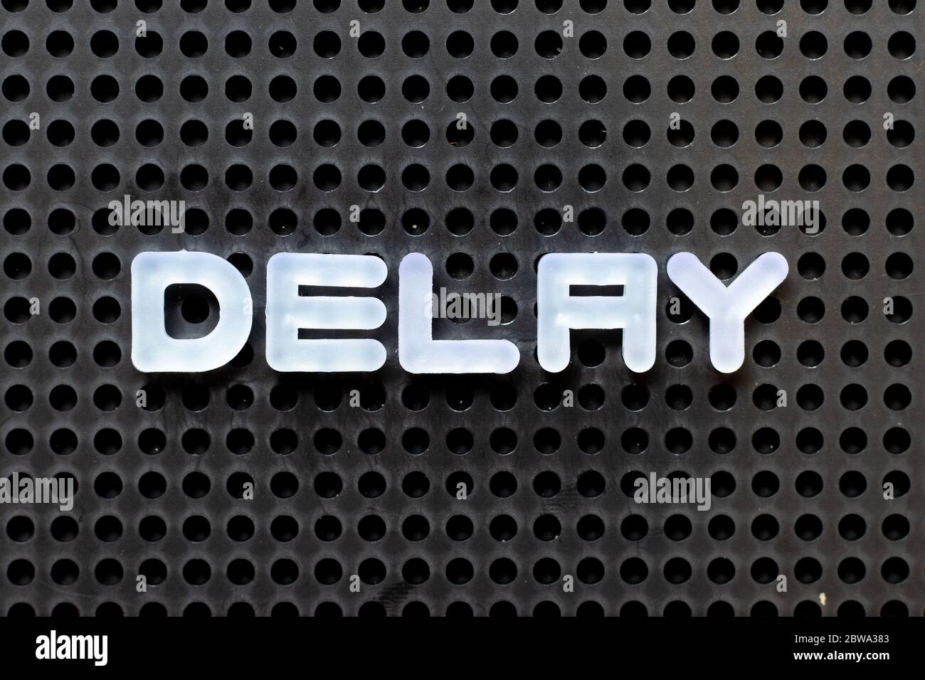 White color alphabet with word delay on black pegboard background Stock ...