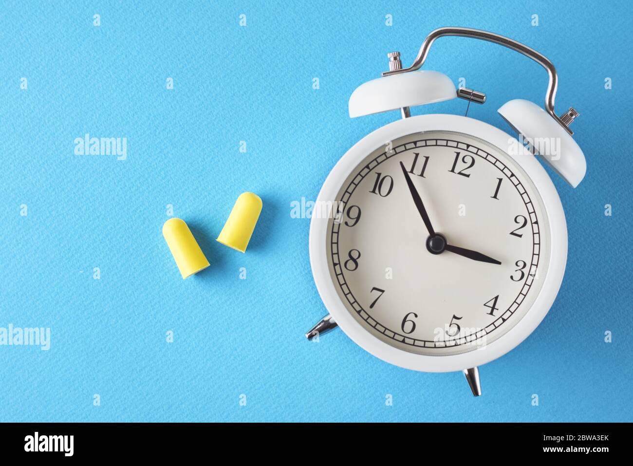 Insomnia problem concept. Alarm clock and ear plugs on blue background ...