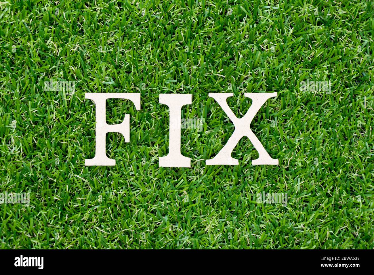 Wood letter in word fix on green grass background Stock Photo - Alamy