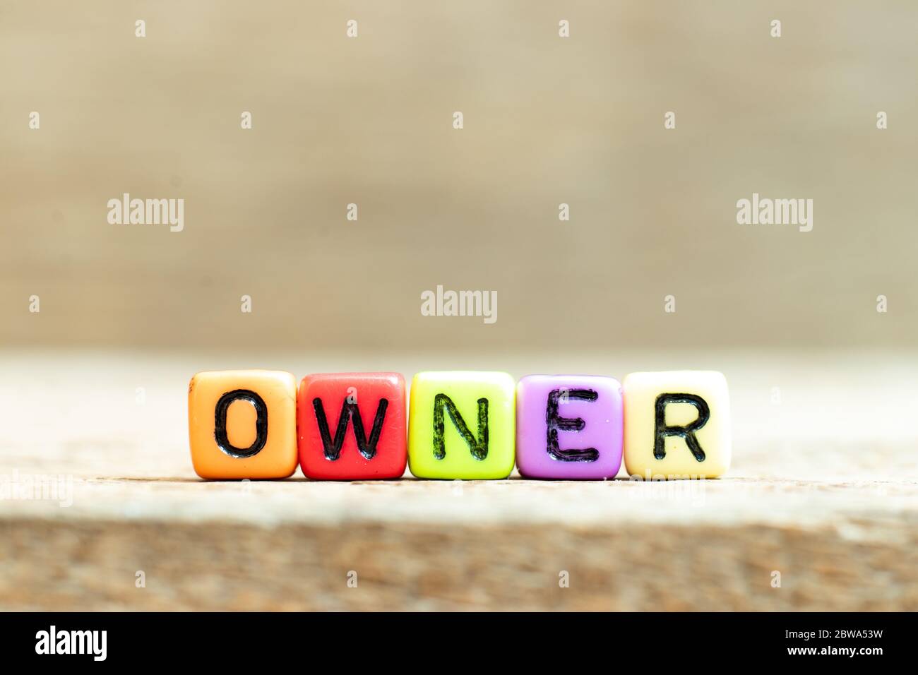 Colorful bead with black letter in word owner on wood background Stock ...