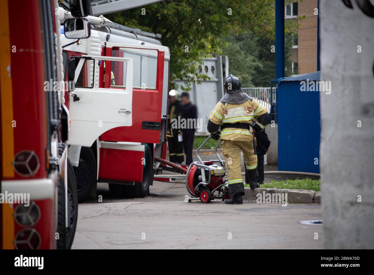 firefighter stands with his back near the fire engines, resting after ...
