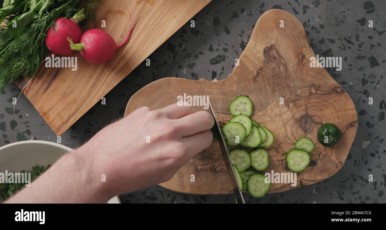 Top view man hands cutting fresh cucucmbers on concrete countertop ...