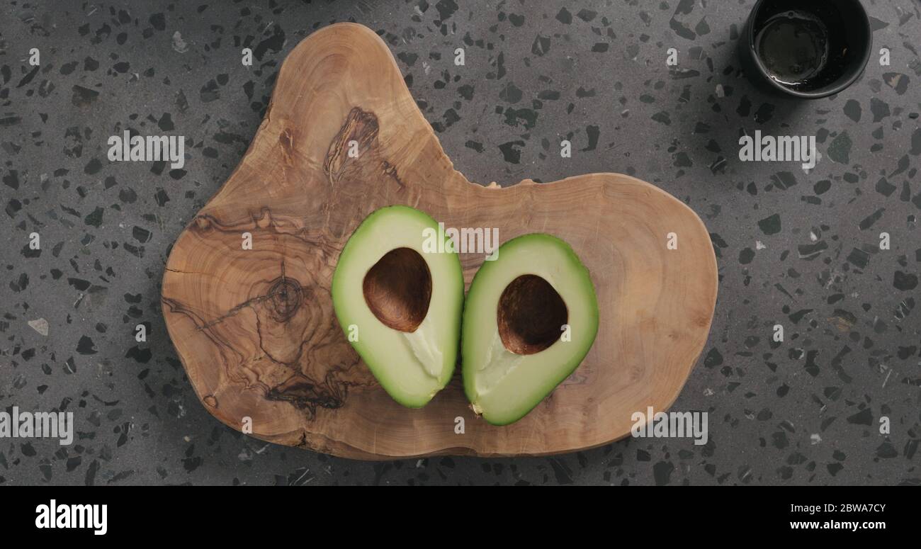 Top view cut in halves and open non ripe avocado on concrete countertop ...