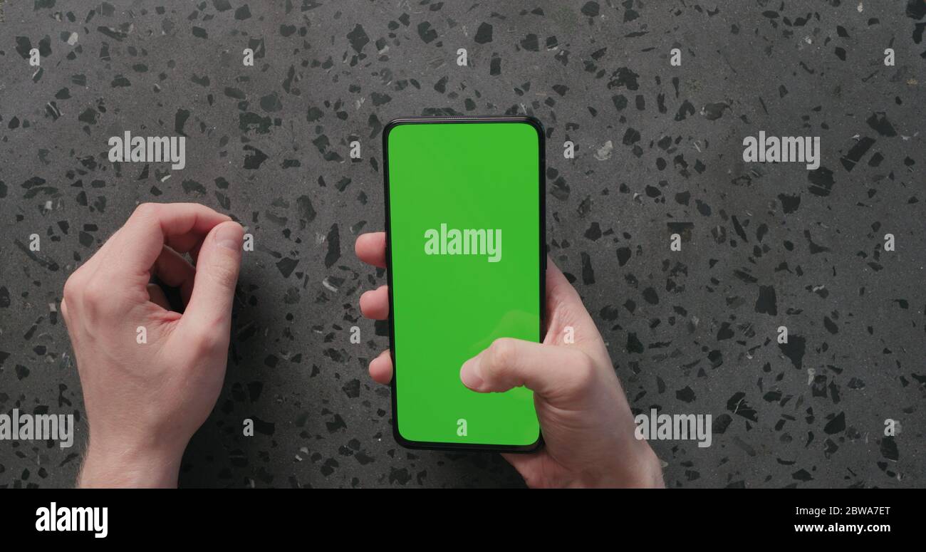 Top view man hand use smartphone with green screen on concrete ...