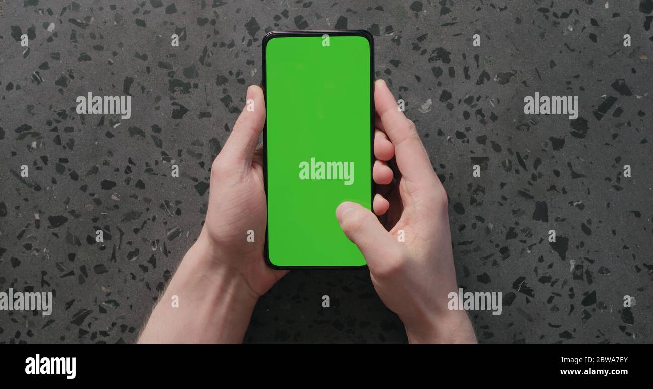 Top view man hand use smartphone with green screen on concrete ...