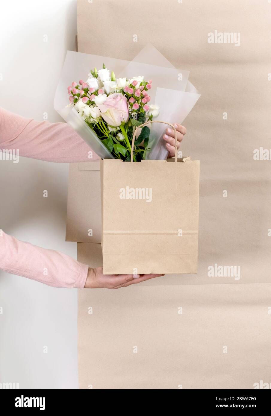 Hands of Worker of Delivery Service Packing Flowers in paper bag for ...