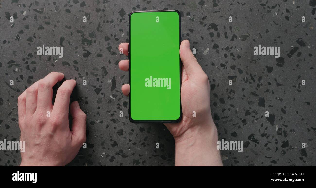 Top view man hand use smartphone with green screen on concrete ...