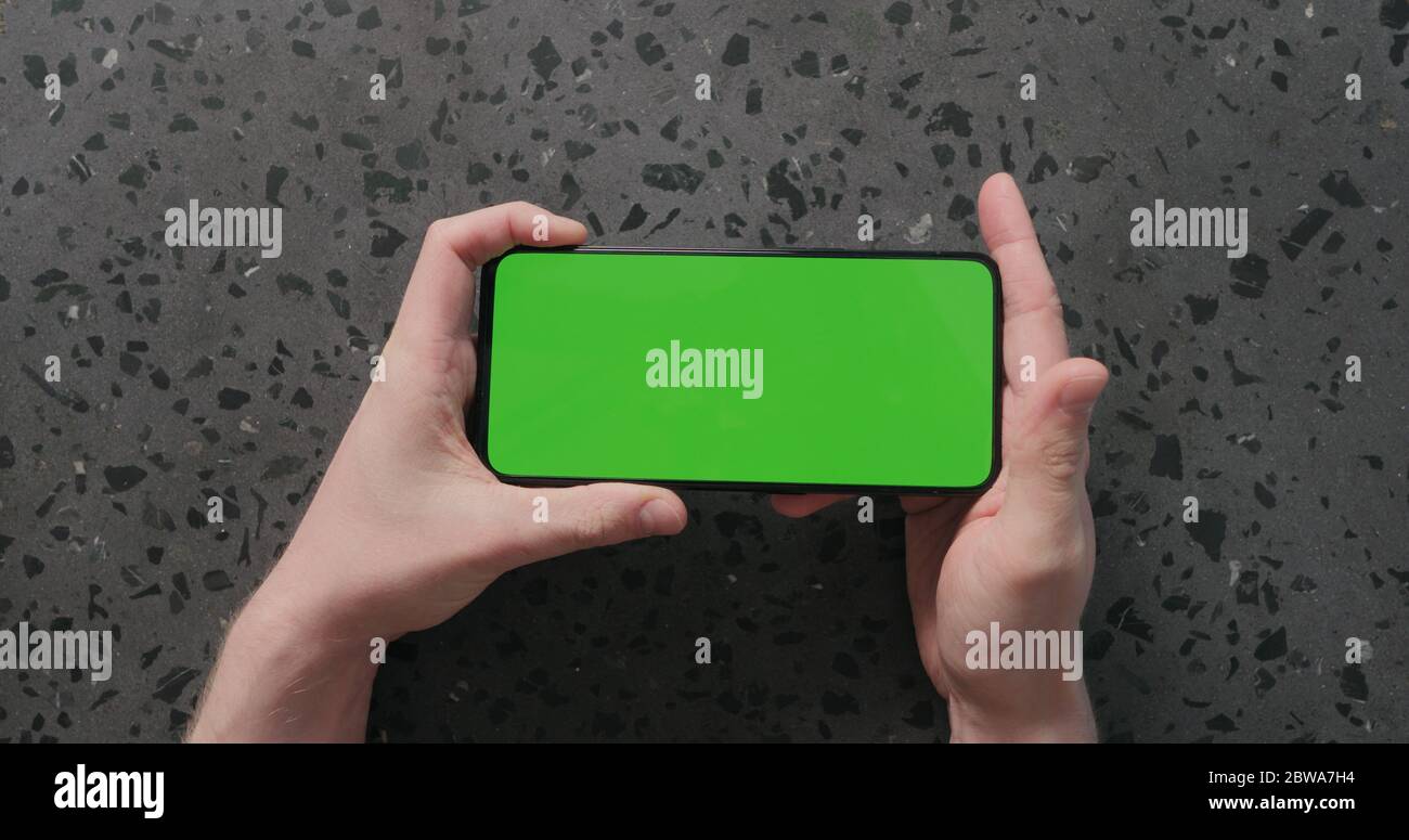 Top view man hand use smartphone with green screen on concrete ...