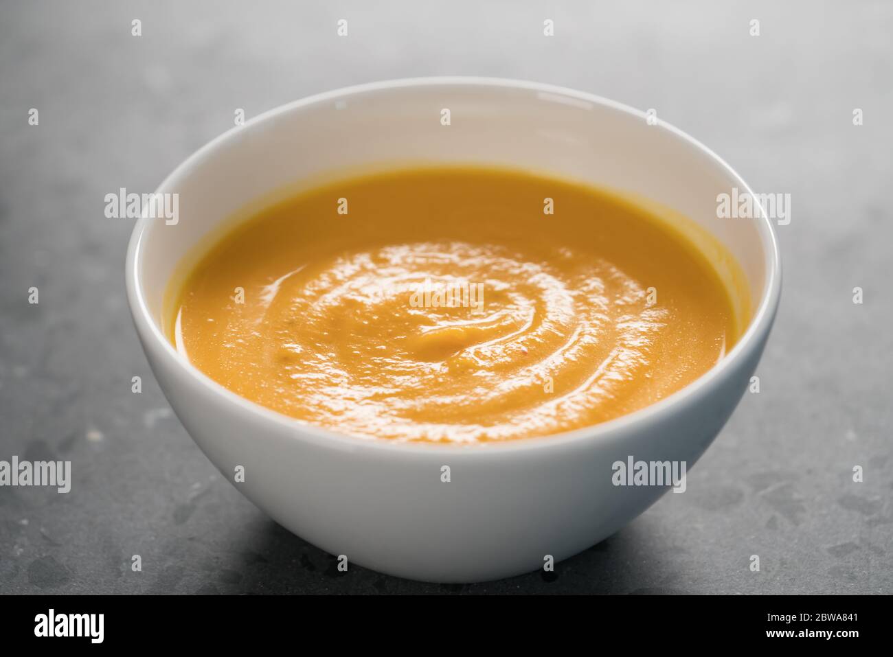 Pumpkin spicy soup puree in white bowl on concrete background Stock ...