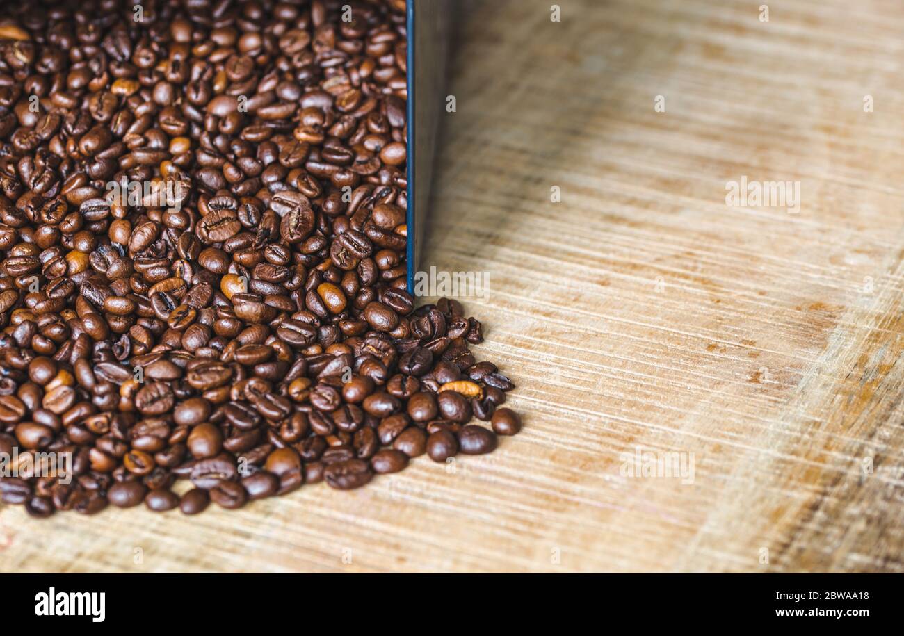 Roasted brown coffee beans inside square tin can spilled on wooden ...