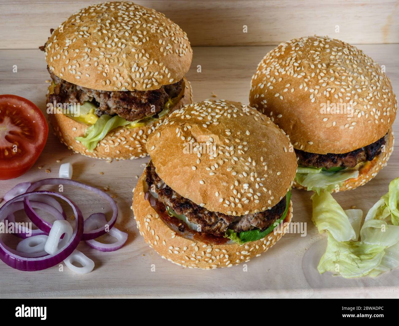 Three fresh burger lay on the board with vegetables Stock Photo - Alamy