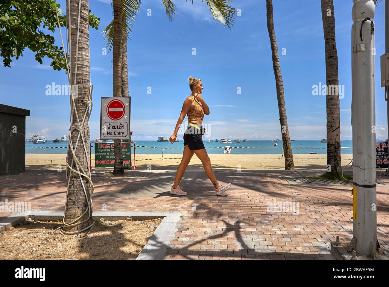 Covid-19 exercise. Woman walking for exercise against a lockdown beach ...