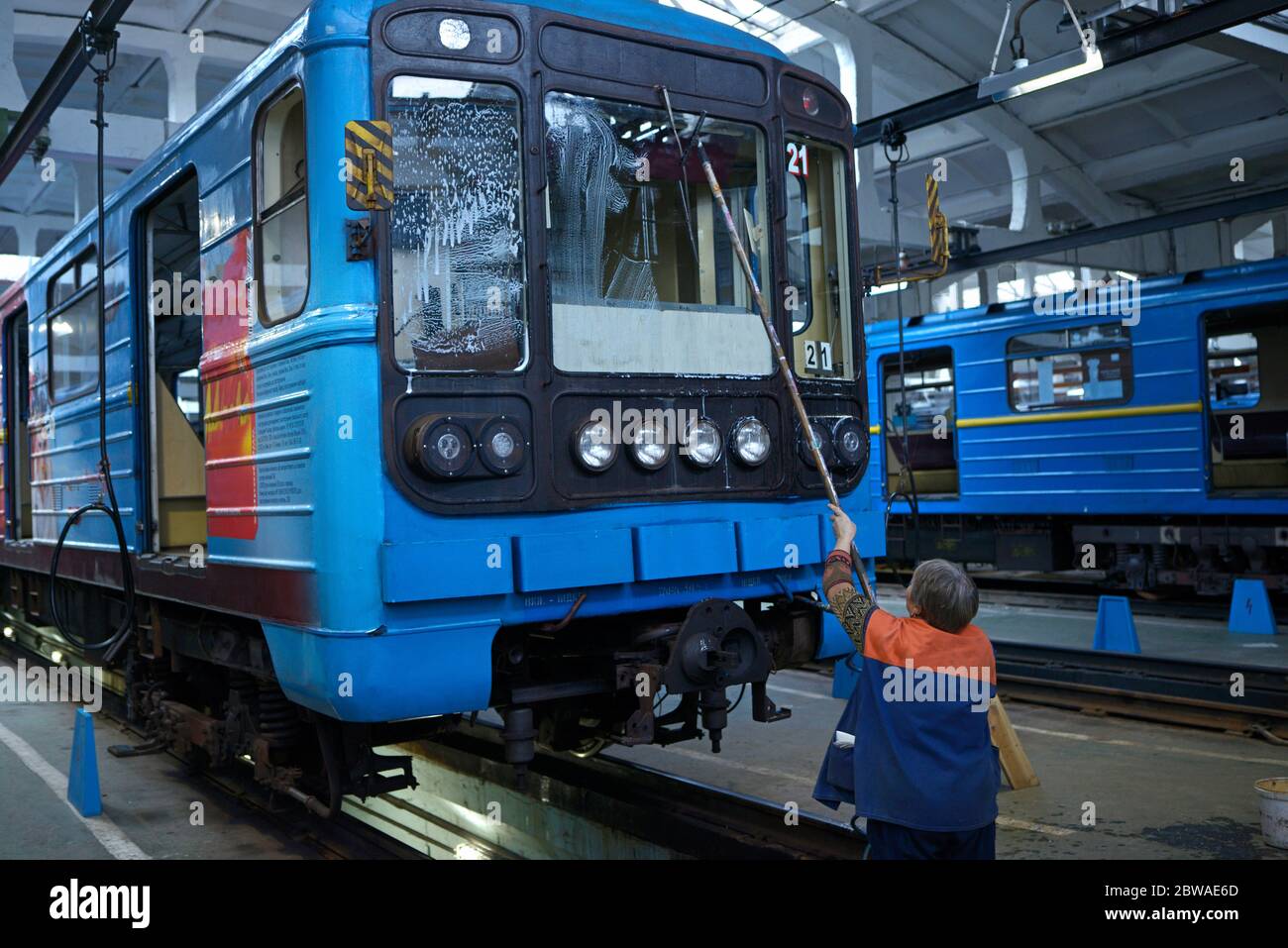 The maintenance hall: female worker washing windows of a subway train ...