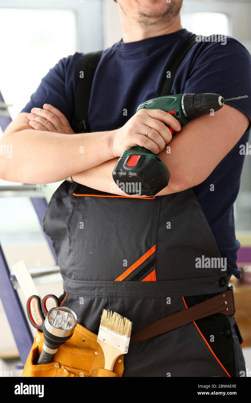 Arms of worker using electric drill closeup Stock Photo - Alamy