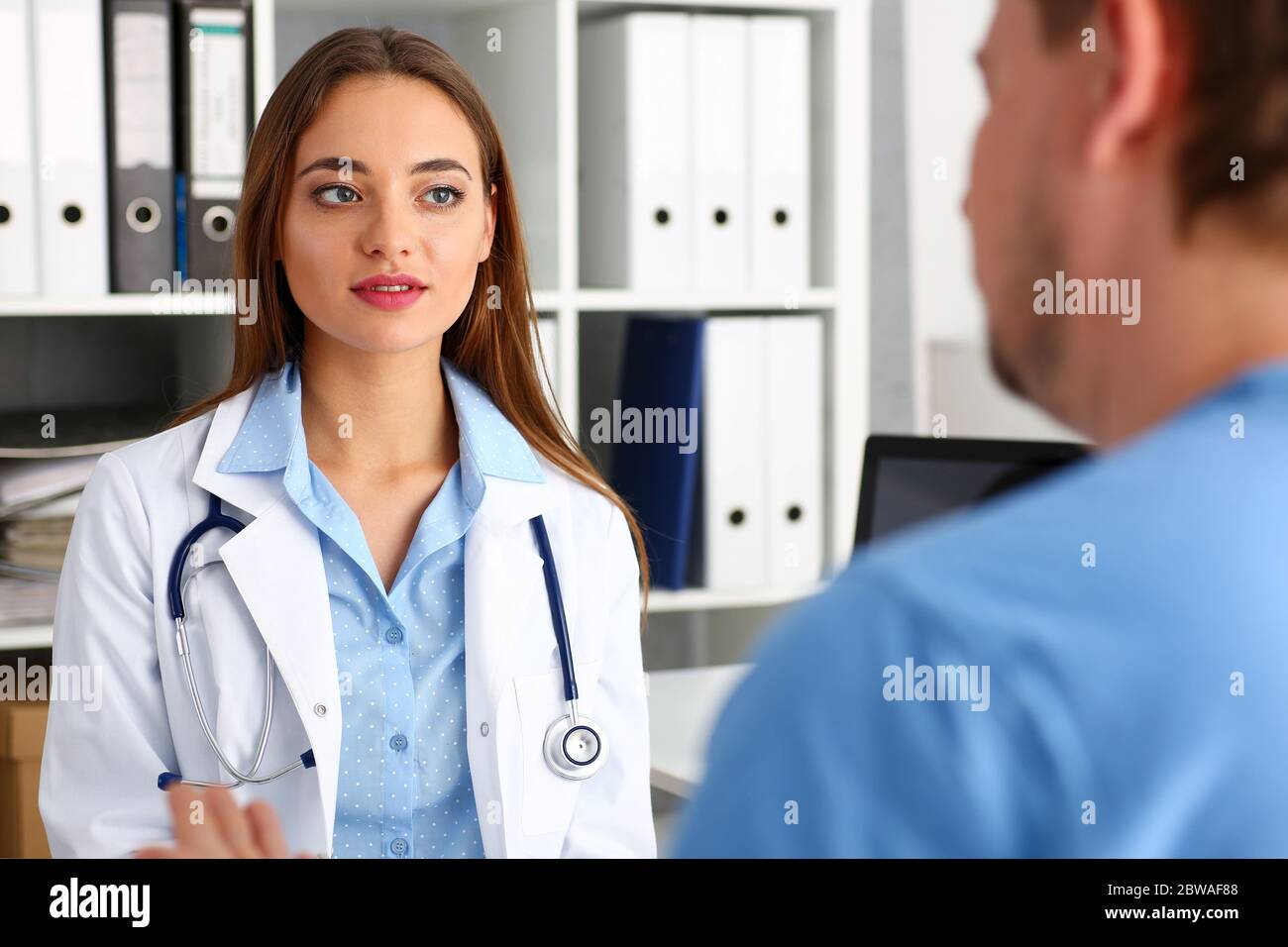 Beautiful female doctor talk with male visitor Stock Photo - Alamy