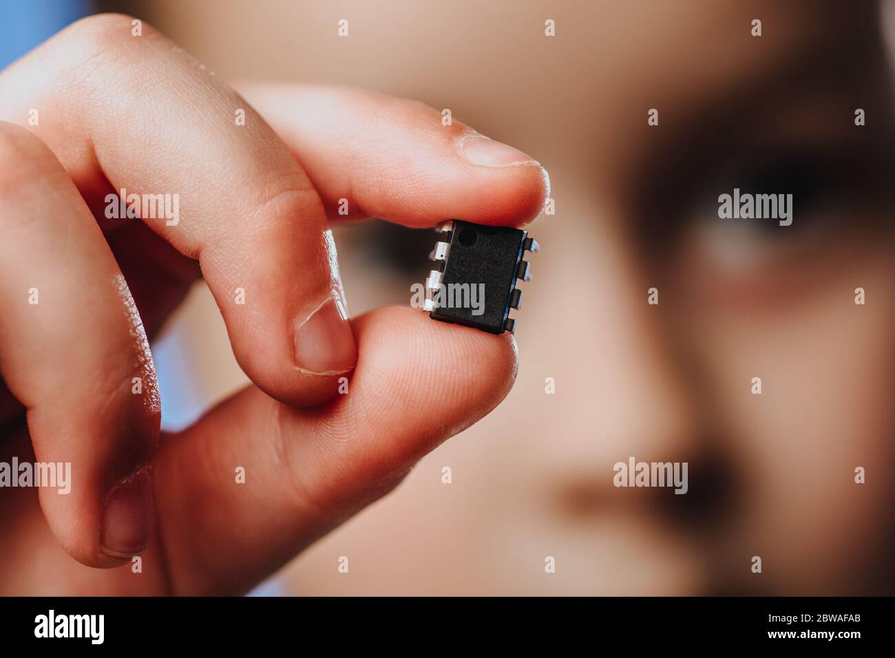 A girl holds in her hand and examines a small black chip. Chipization ...