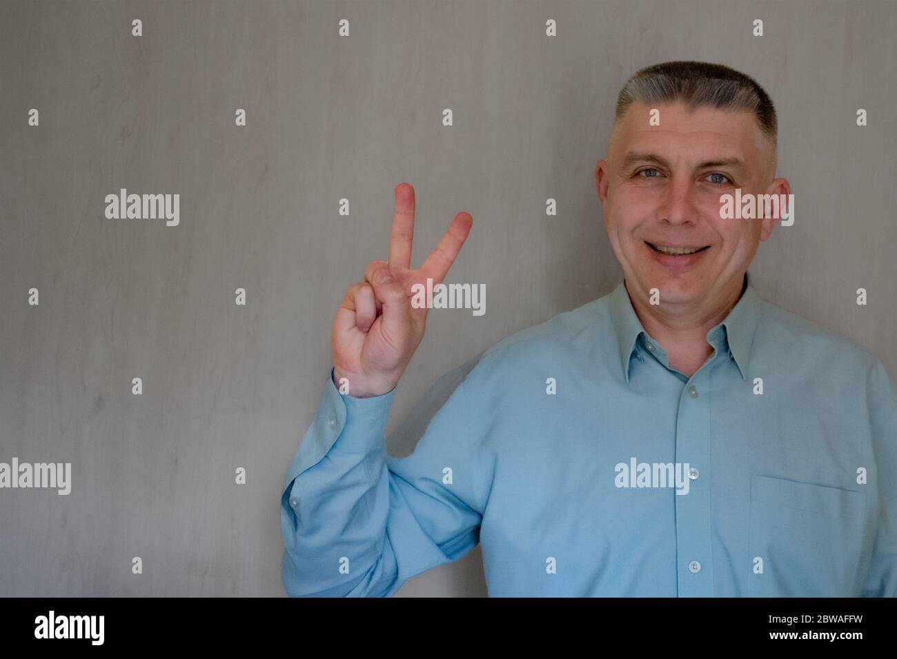 Middle aged man portrait. Victory sign gesture of 40 years man looking ...