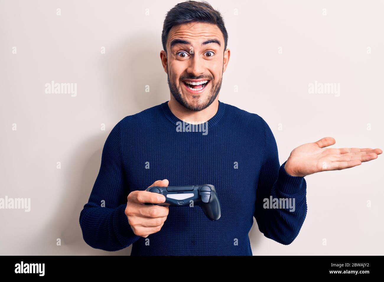 Handsome gamer man with beard playing video game using gamepad over ...