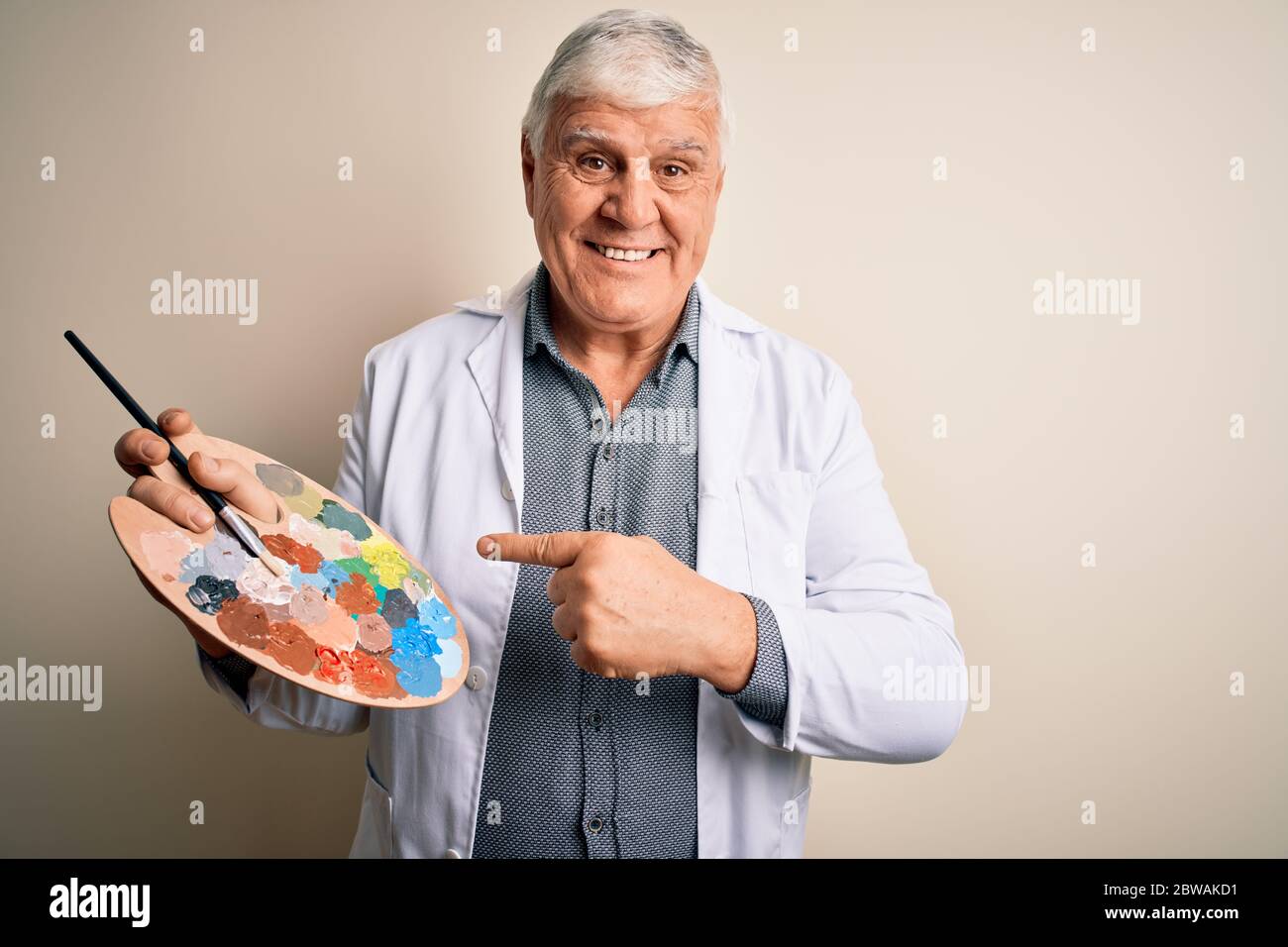 Senior handsome hoary painter man painting using brush and palette with ...