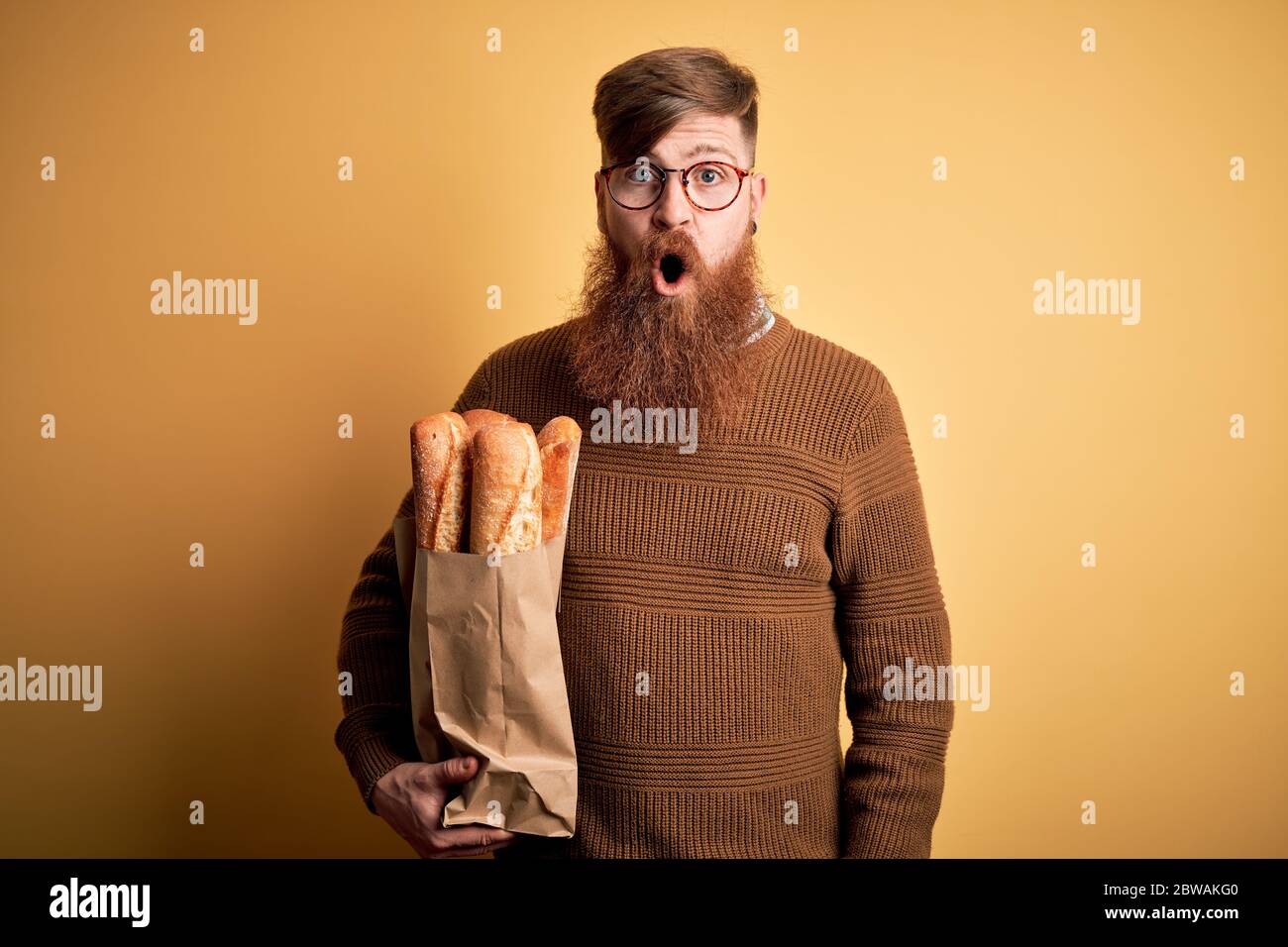 Irish redhead man with beard holding groceries paper bag of bread over ...