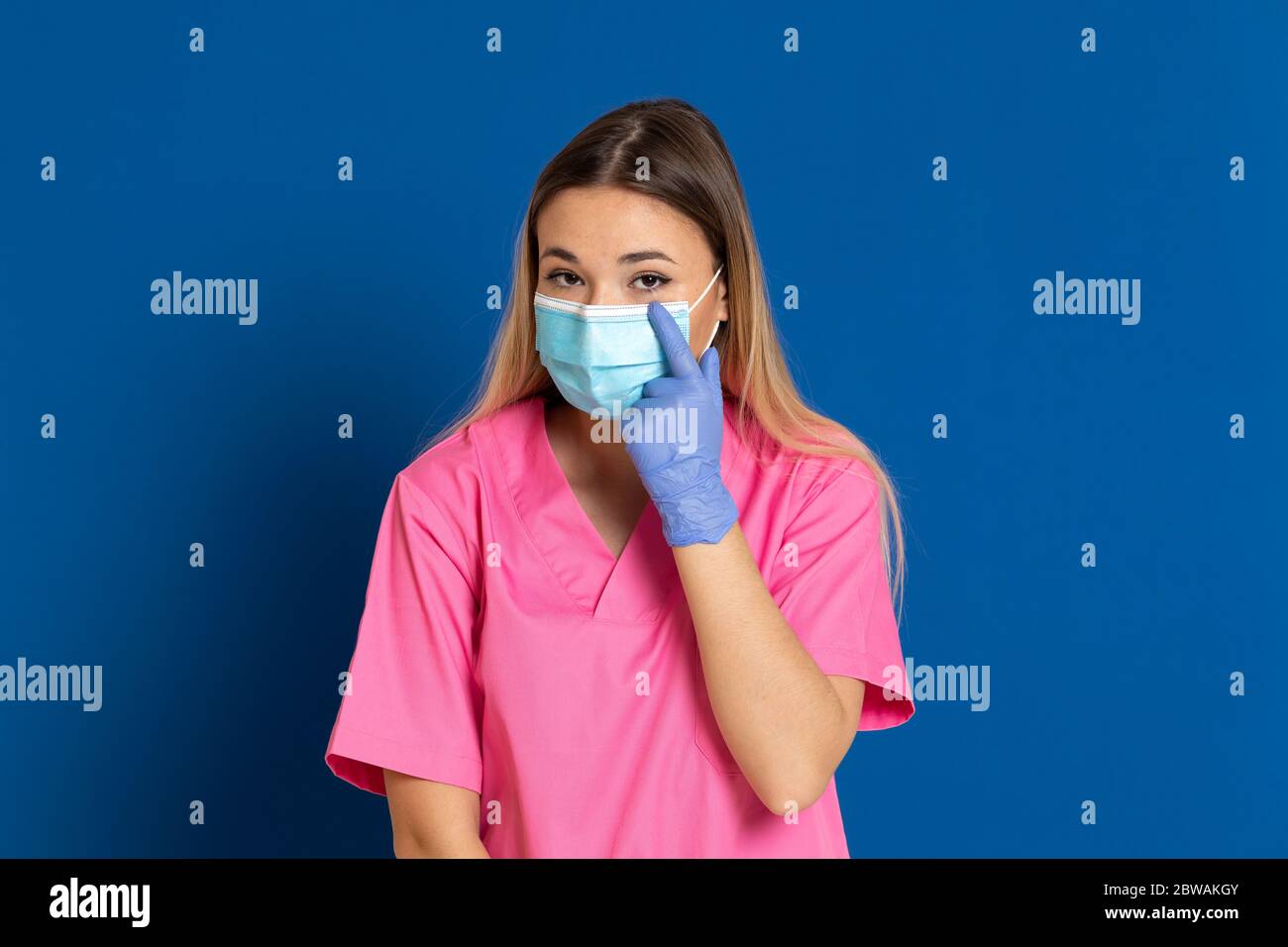Young doctor wearing a mask face and a pink uniform on a blue ...