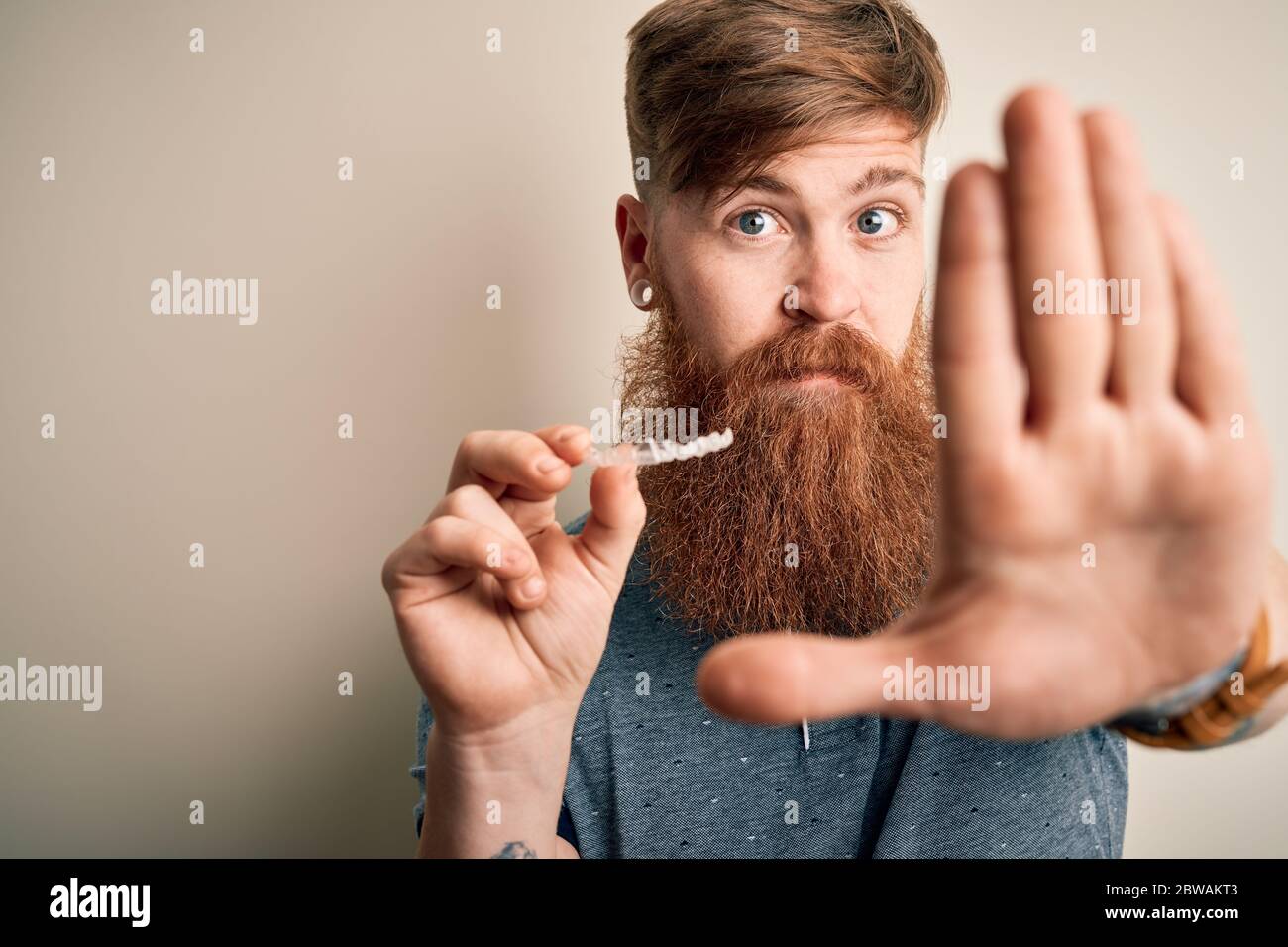 Irish redhead man with beard holding dental invisible aligner for tooth ...