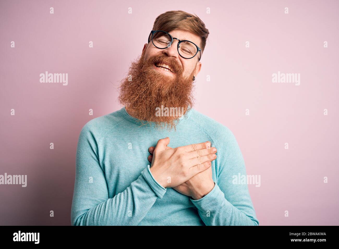 Handsome Irish redhead man with beard wearing glasses over pink ...