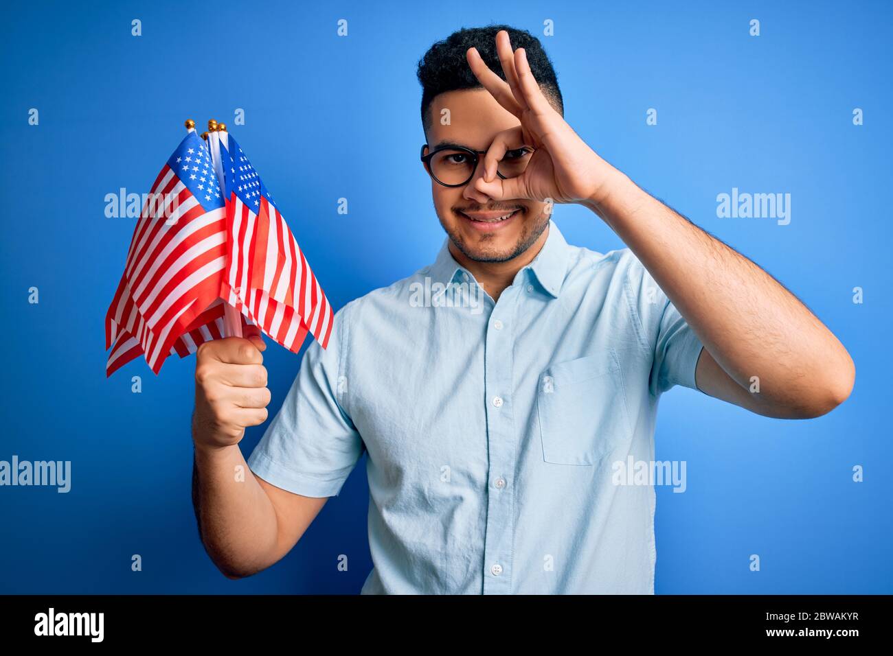 Young handsome patriotic man holding united states flags celebrating ...