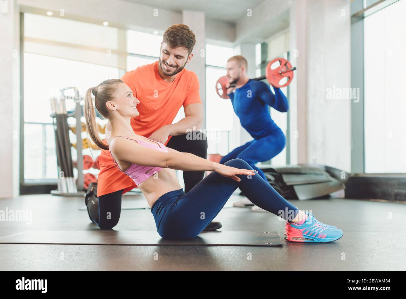 Personal coach helping fit woman in the gym with her exercises Stock ...